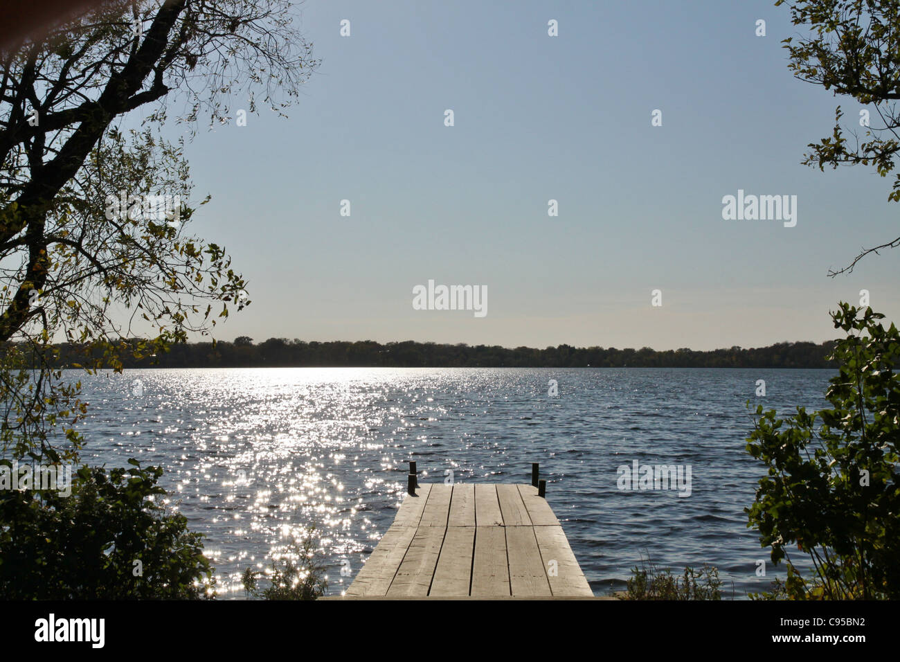 A dock on a sun dappled lake Stock Photo - Alamy