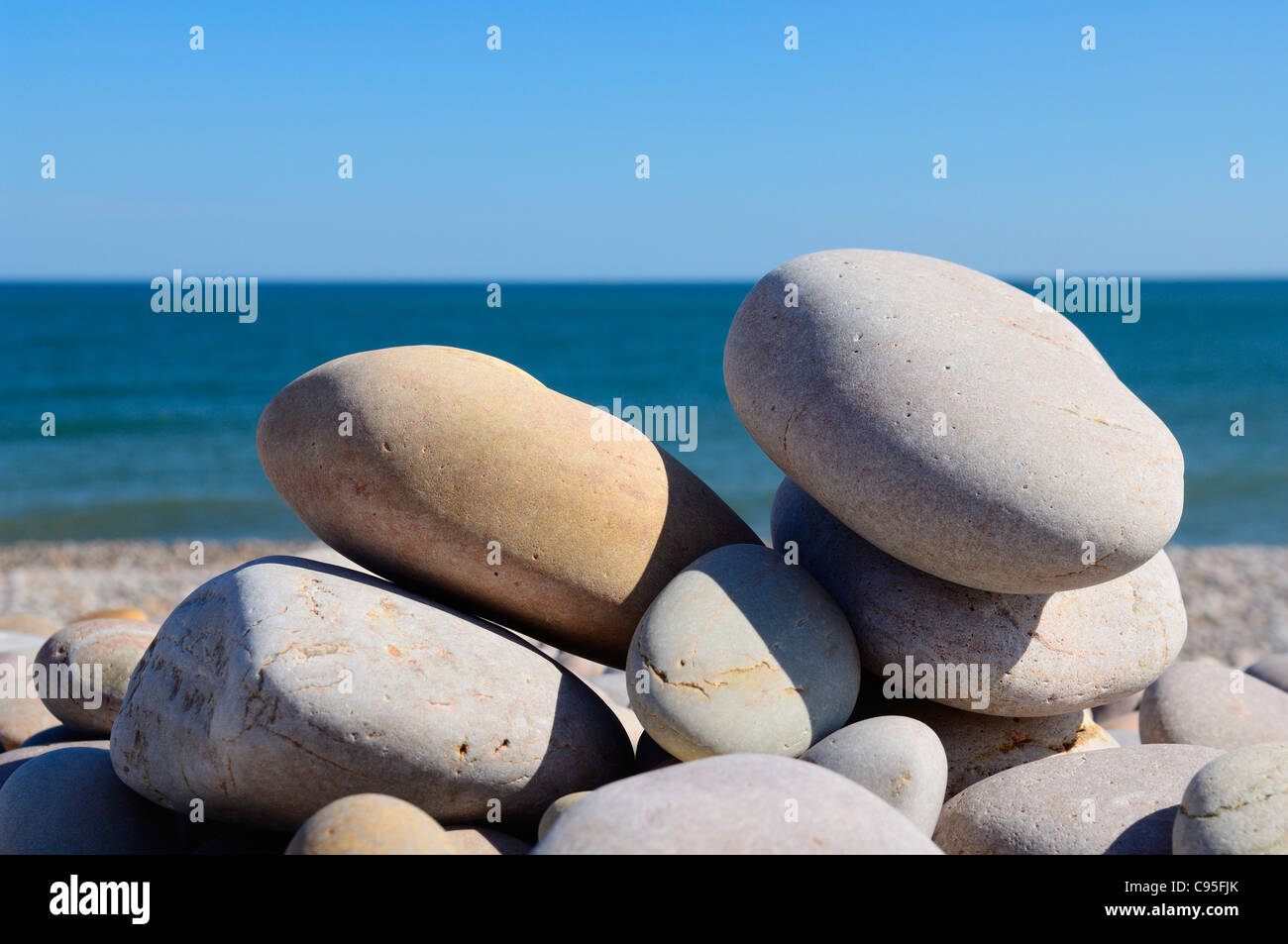 Pebbles stacked on a beach under a clear blue sky Stock Photo - Alamy