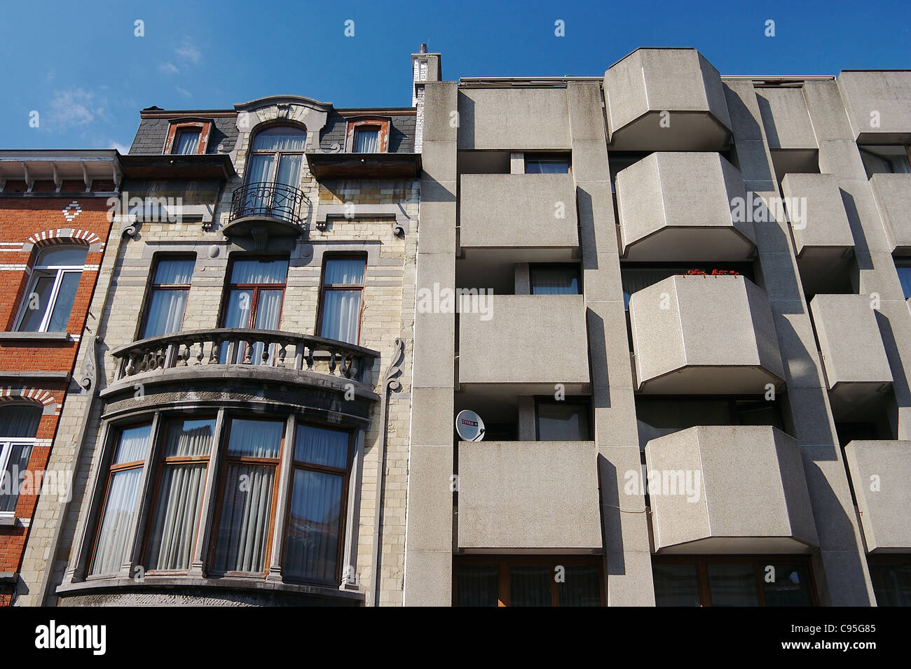 A modern, concrete apartment building next to old architecture in ...
