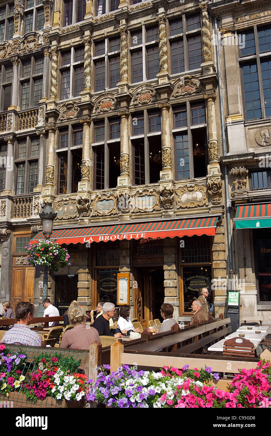 People sit at a cafe beside the ornate buildings of the Grand Place ...