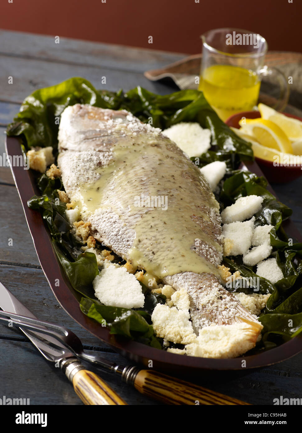 Whole salt crusted red snapper served on a bed of greens Stock Photo ...