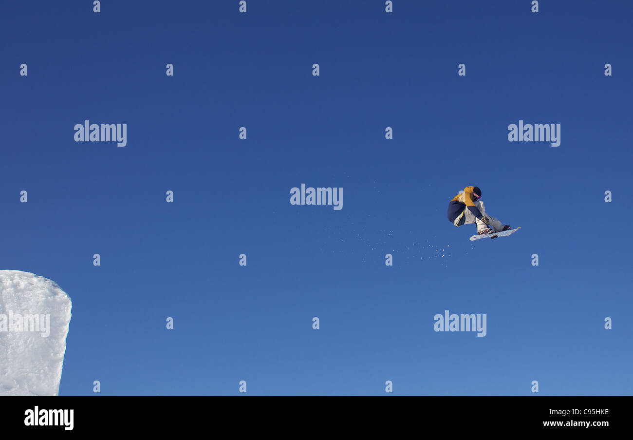A snowboarder snowboarding in action against a blue sky and mountain ...