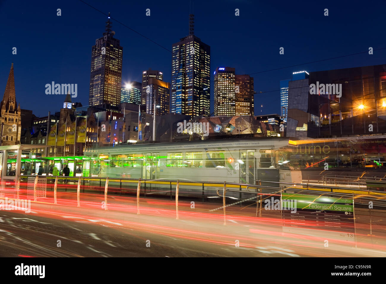 Traffic and tram light trails on Swanston Street with city skyline in ...