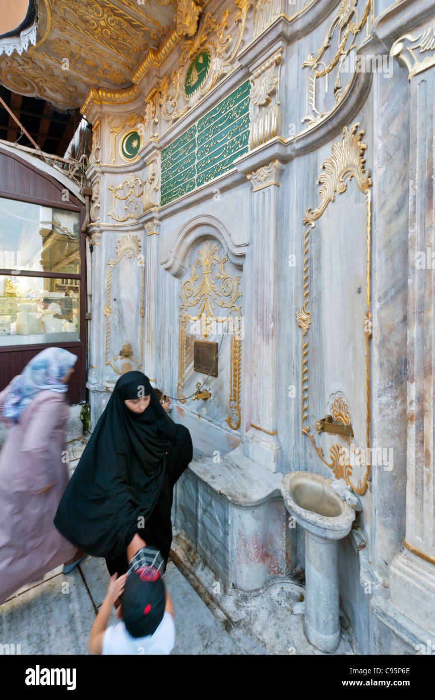 A veiled women in front of The Hatice Turhan Valide Sultan Sebil and ...