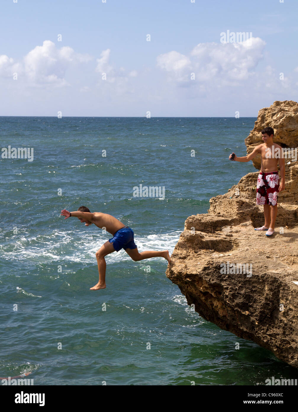Young man Jumping into the sea water from rock in Mallorca Majorca ...