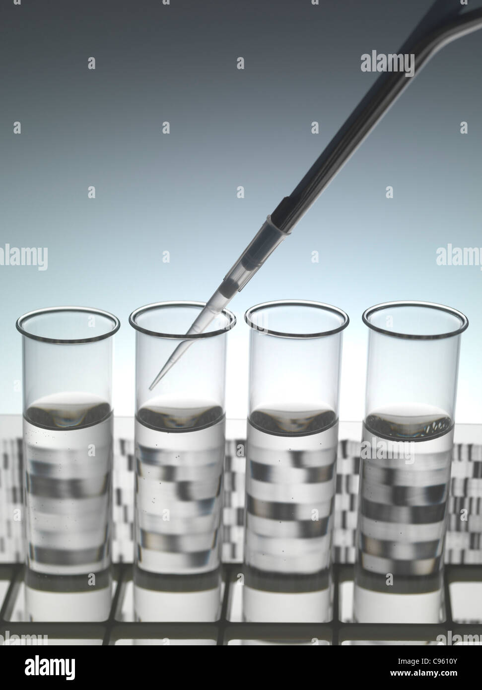 Genetic research. Pipetting into a test tube sitting in front of a DNA ...