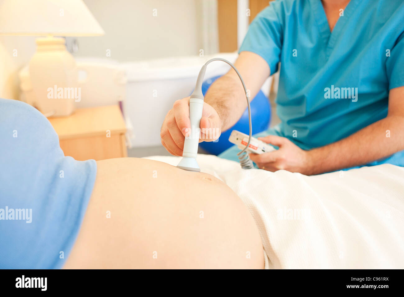 Obstetric examination. Midwife using a doppler monitor to listen to a ...