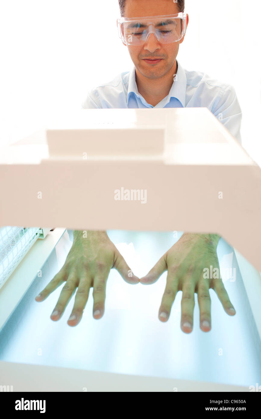 Phototherapy booth. Patient with their hands in a phototherapy box ...