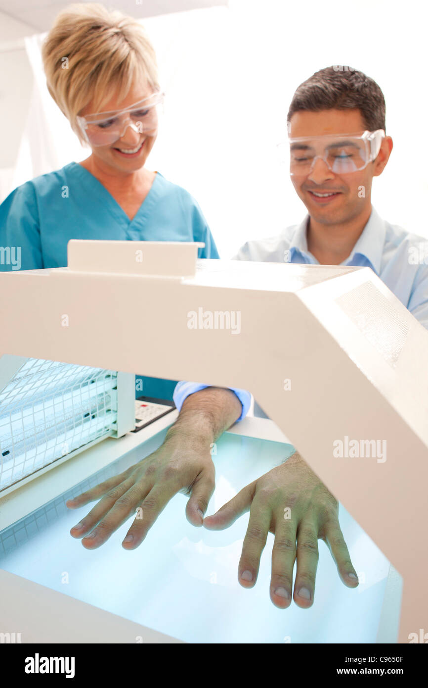 Phototherapy booth. Patient with their hands in a phototherapy box ...