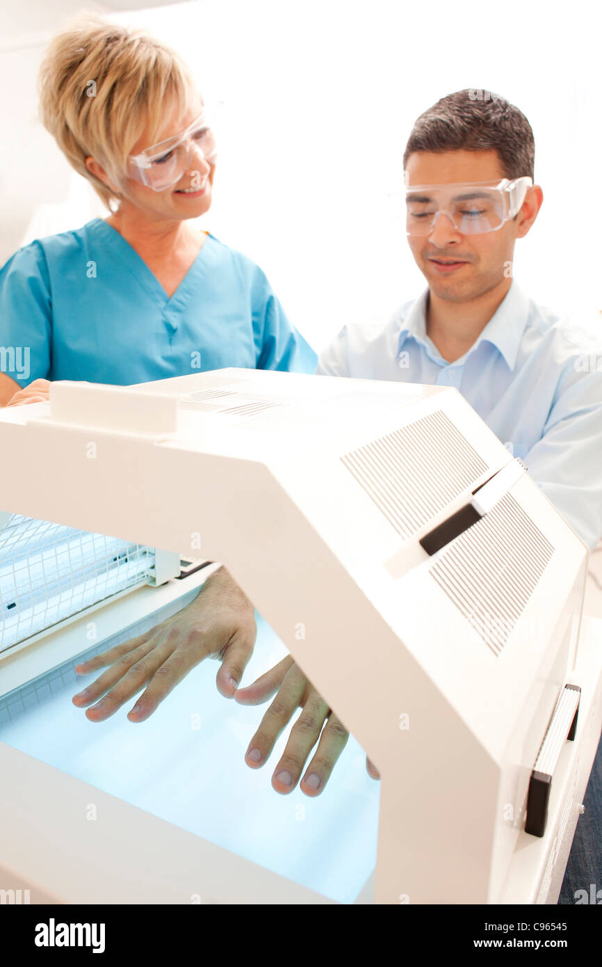 Phototherapy booth. Patient with their hands in a phototherapy box ...
