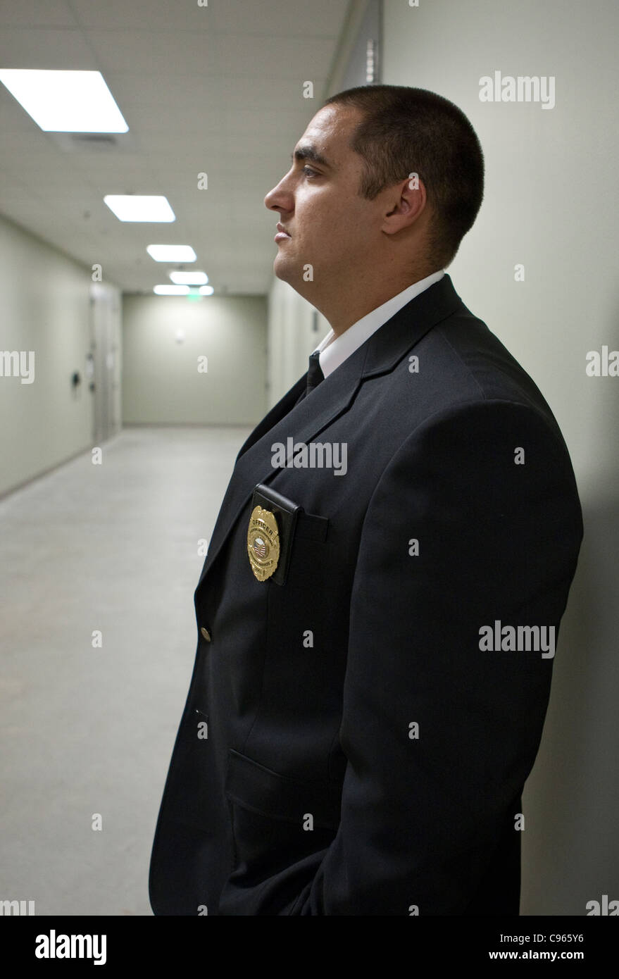Hispanic male security guard stands alone in hallway inside electric ...
