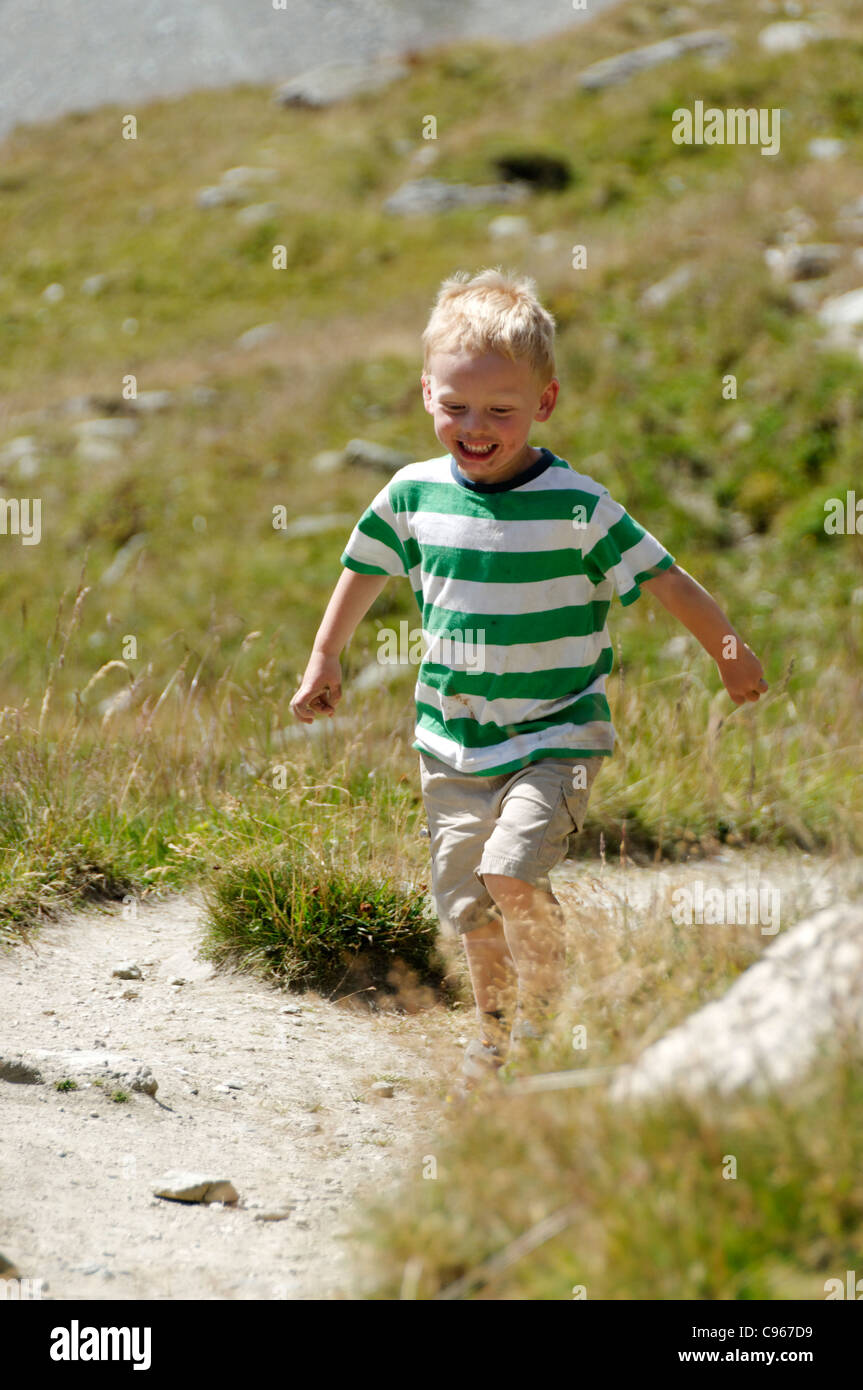 A young boy running along a mountain track Stock Photo - Alamy