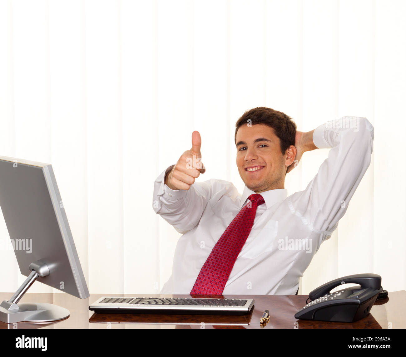 A successful young manager sitting at a desk and smiles Stock Photo - Alamy
