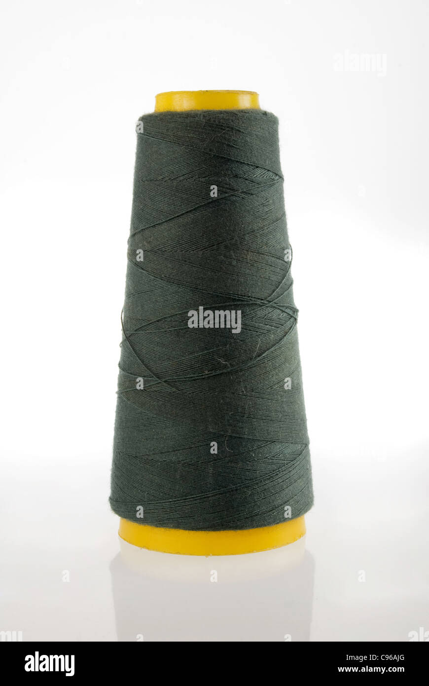 A bobbin of dark green thread isolated with its reflection on white ...