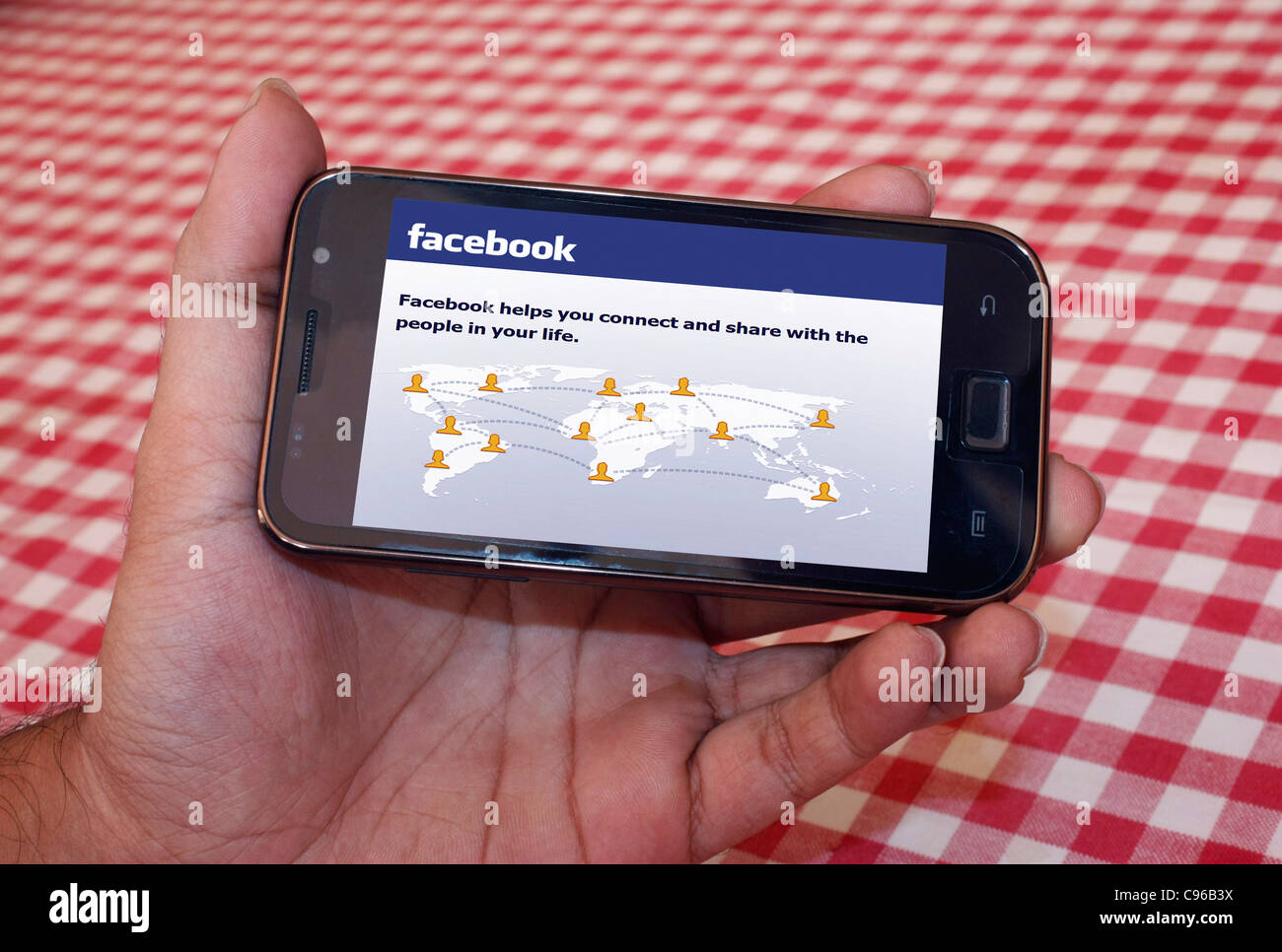 Person holding a smart phone displaying the home page of facebook ...