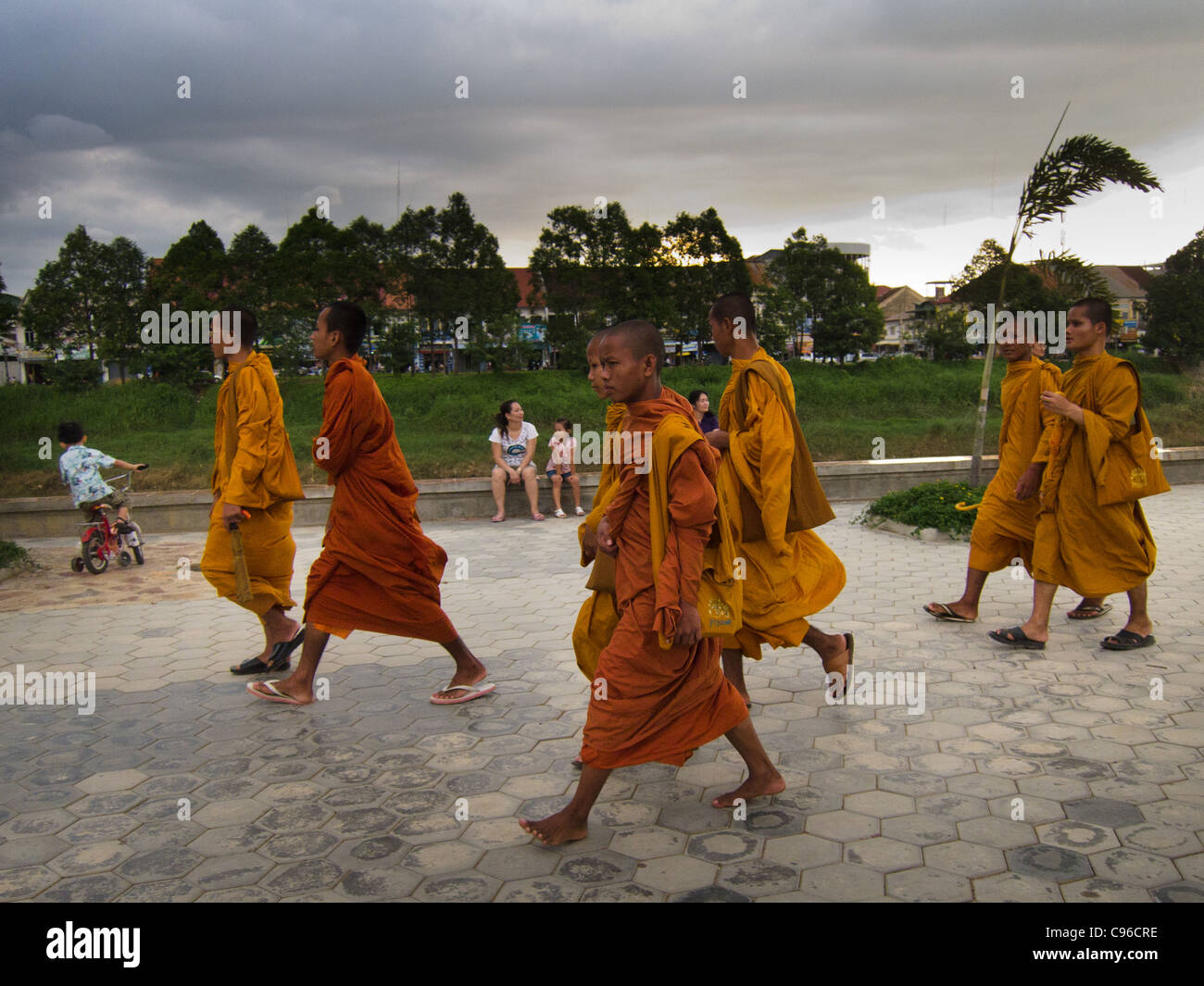 Young Buddhist monks are walking along the river in Battambang, it's ...