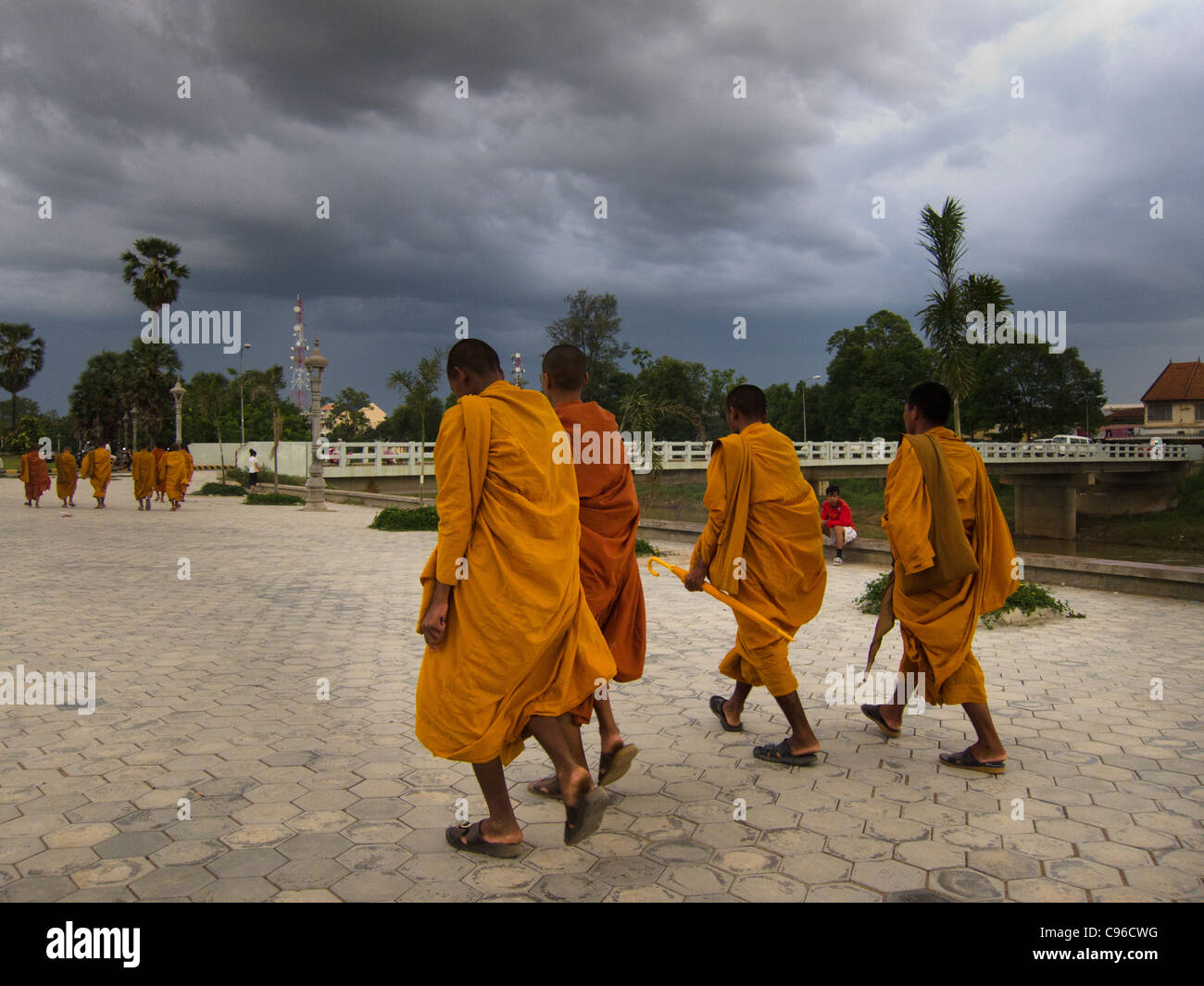 Young Buddhist monks are walking along the river in Battambang, it's ...