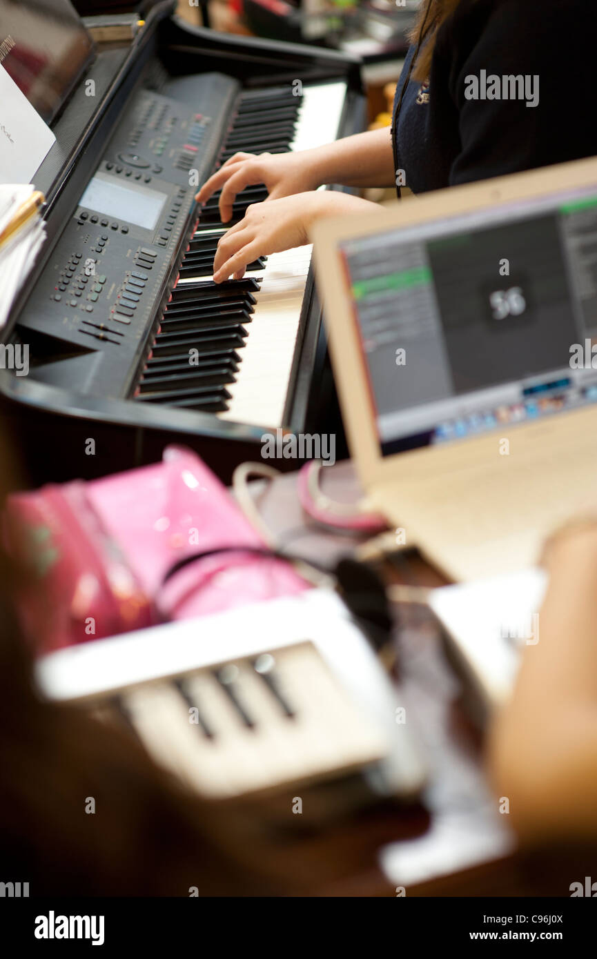 Secondary school children playing keyboards in a music technology class ...