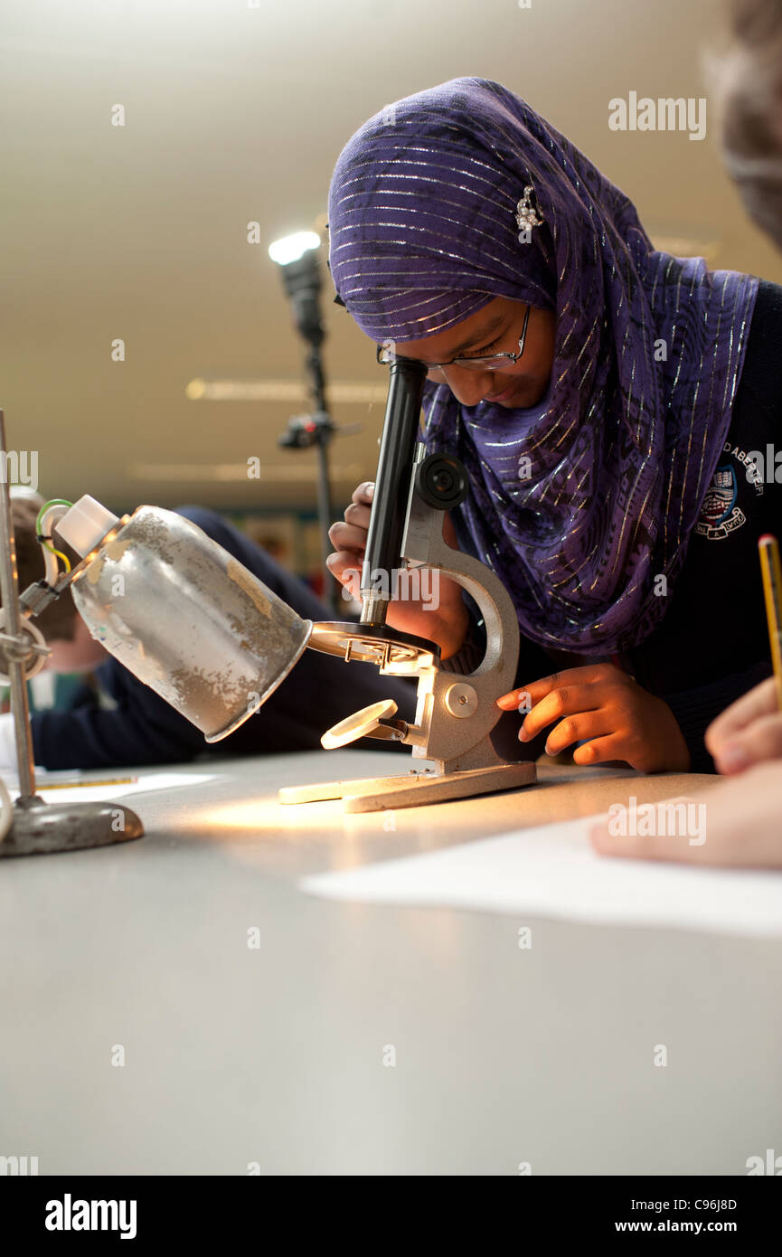 Secondary school Muslim girl looking through a microscope in a science ...
