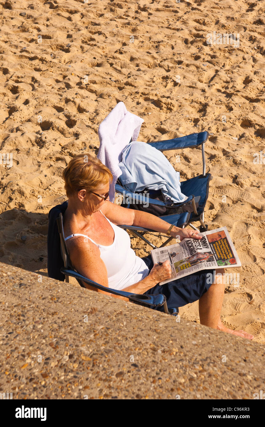 A woman reading a newspaper on a Uk beach Stock Photo - Alamy