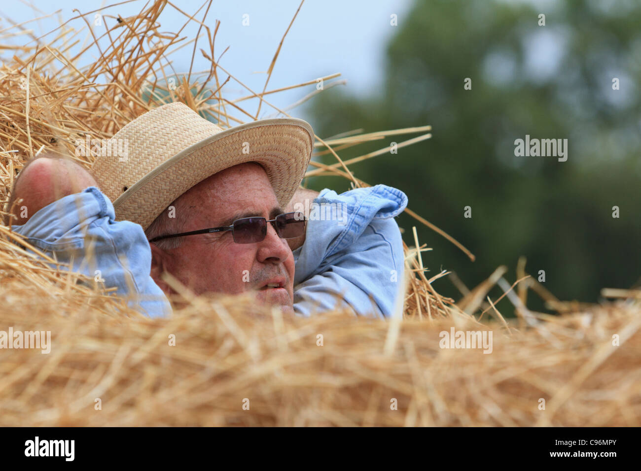 Man in hat relaxing in hay Stock Photo - Alamy