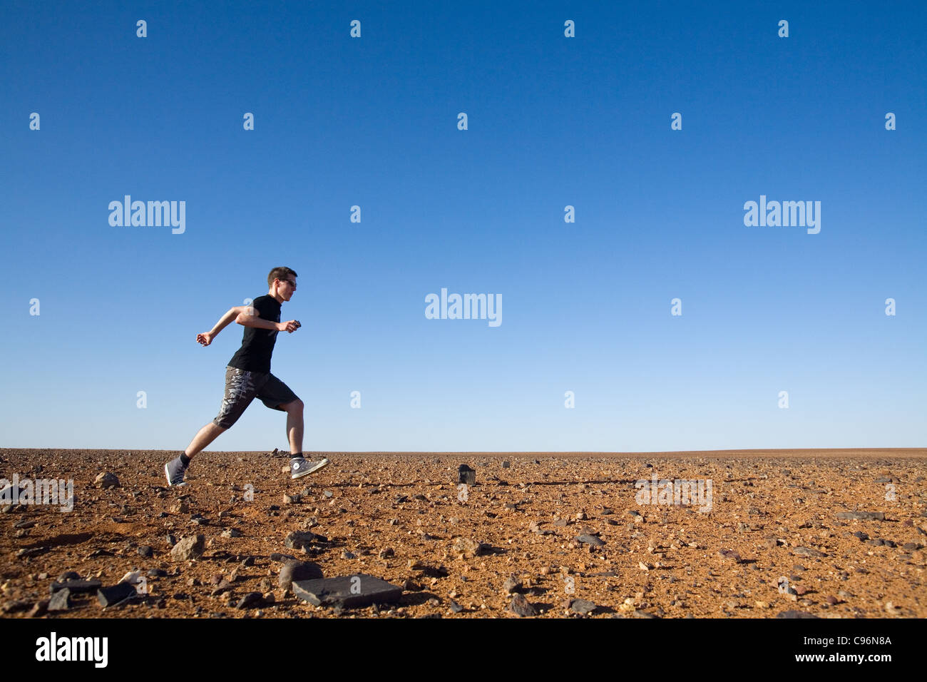 Man running across the desert landscape of the Moon Plain. Coober Pedy ...