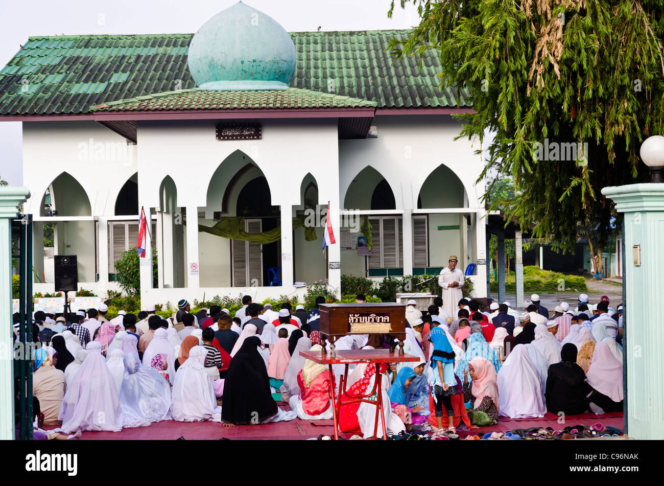 Mosque with outdoor religious service in session. Dozens of people ...
