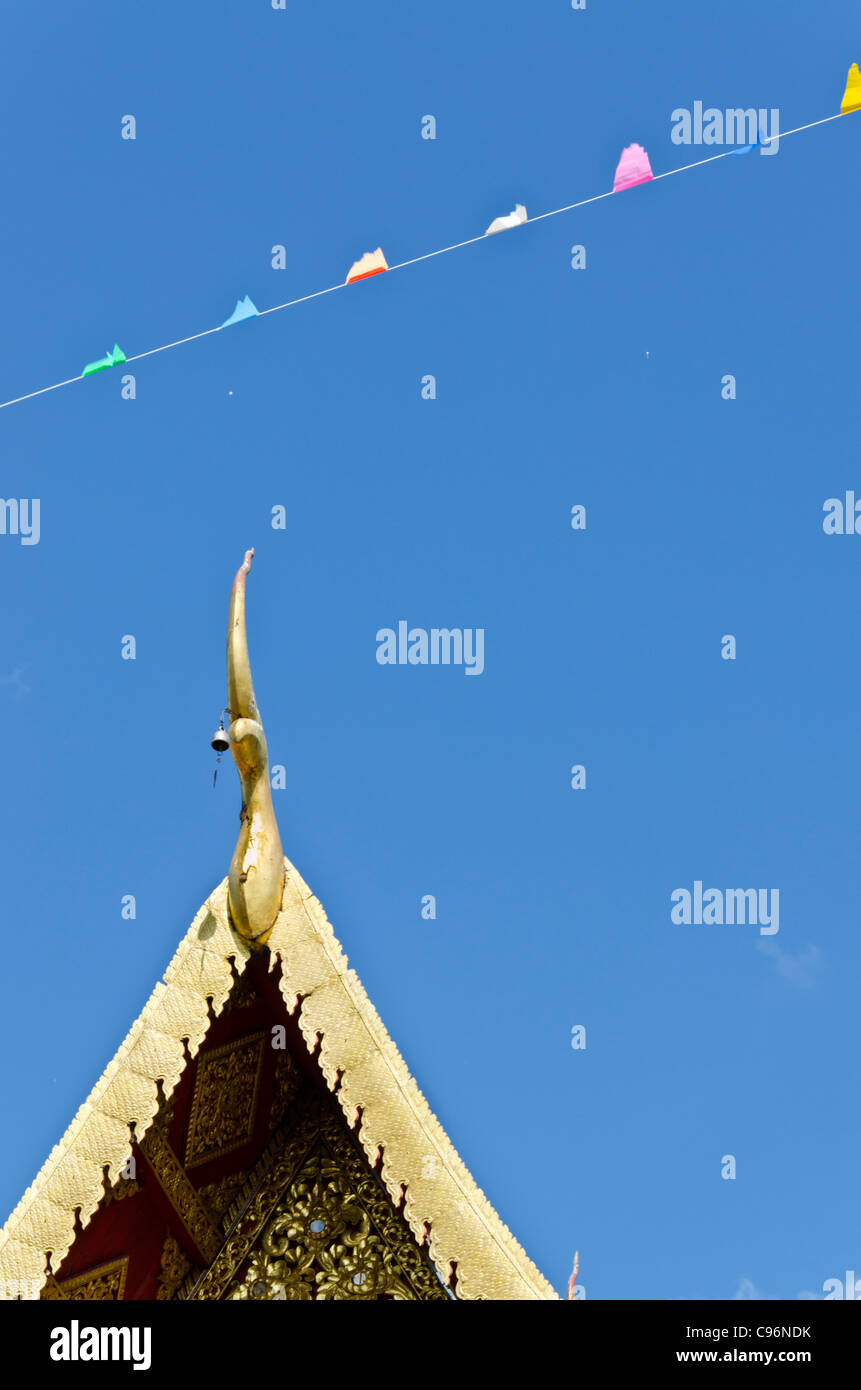 Top of golden Buddhist temple with chofa and string of bunting flags ...