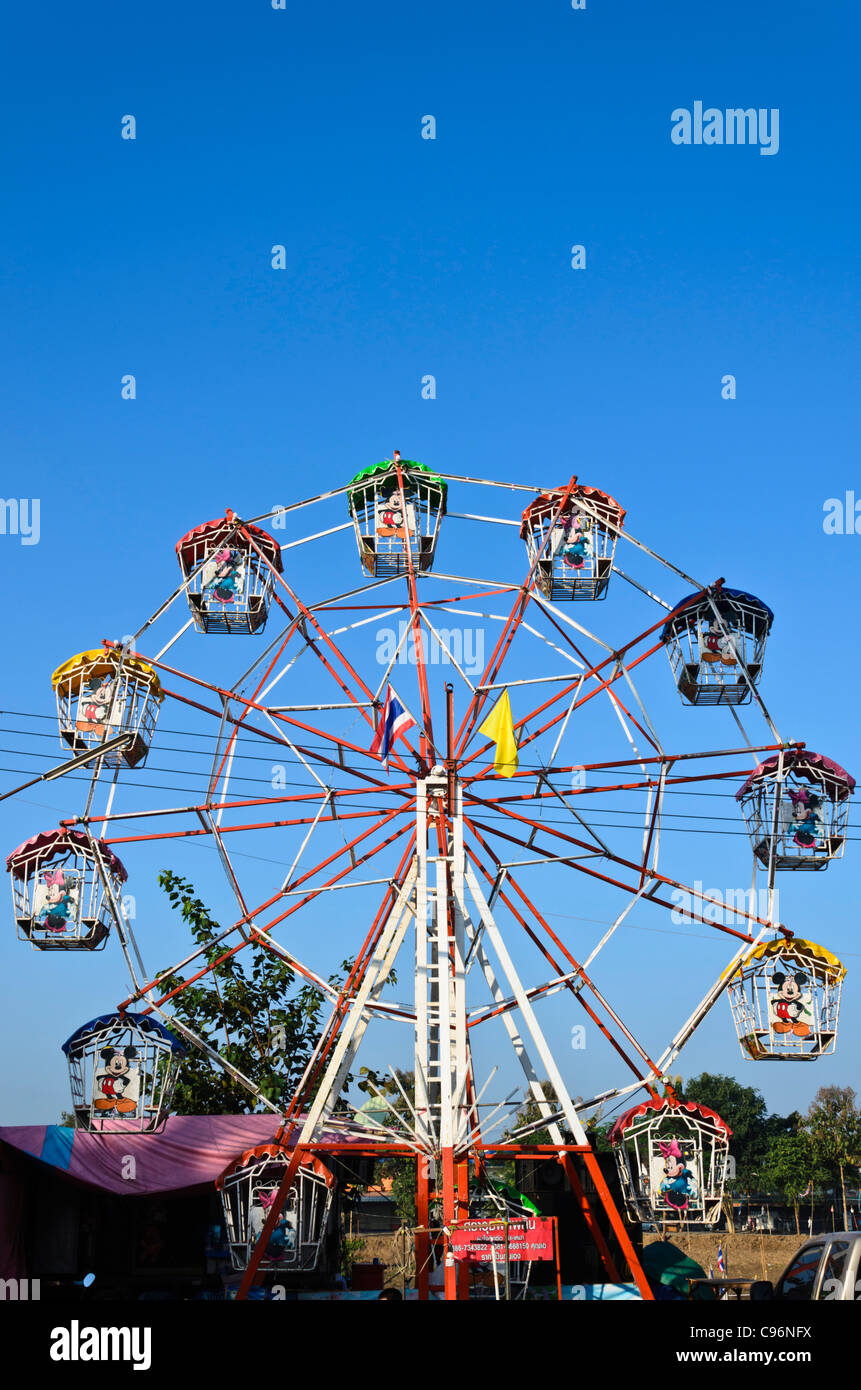 Small colorful ferris wheel with cartoon characters and clear blue sky ...