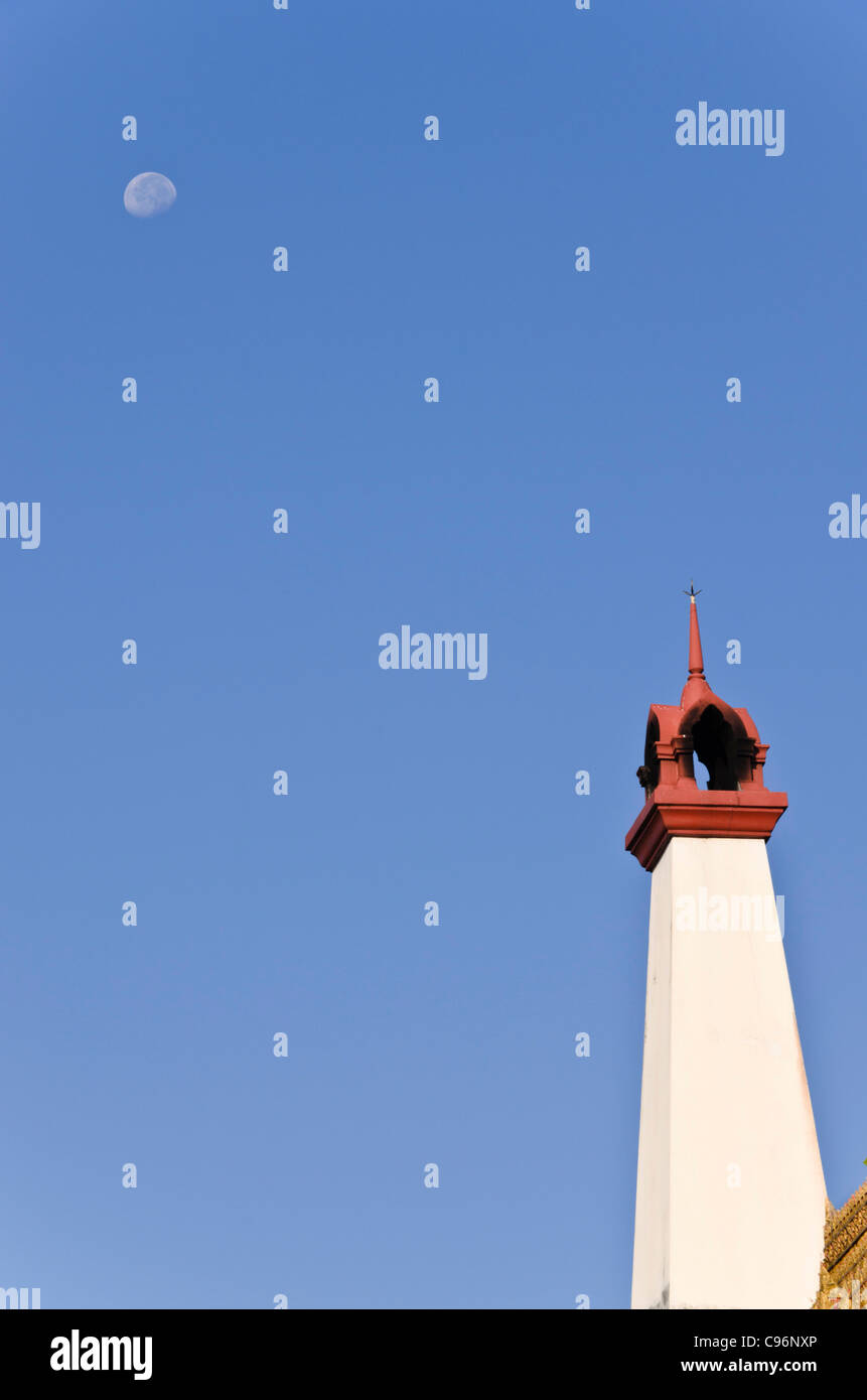 White chimney of Buddhist crematorium with the moon above it in clear ...