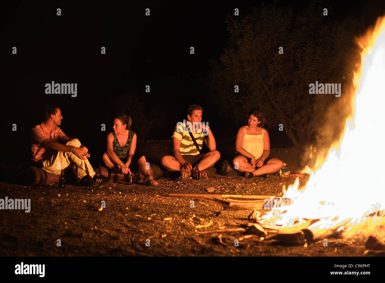 Tourists sit around the campfire in the Australian outback. Curtin ...