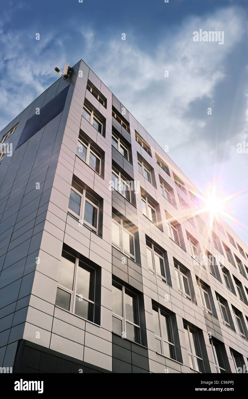 Grey office building and rays of sun in moody sky Stock Photo - Alamy