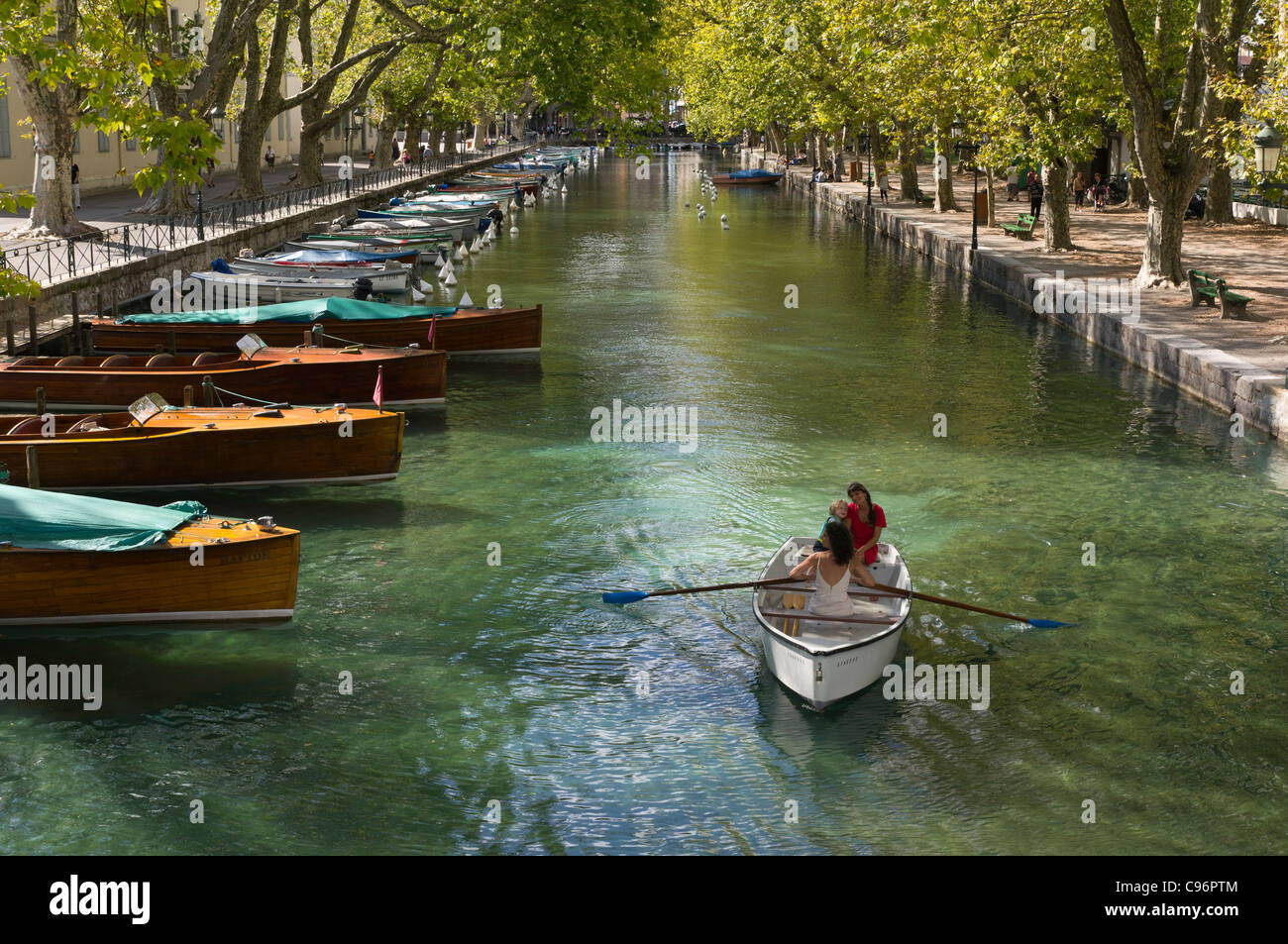 Two young French women in a rowing boat with a small boy, row along a ...