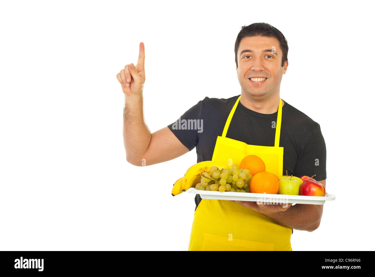 Smiling fruiterer holding fruits and pointing upwards isolated on white ...