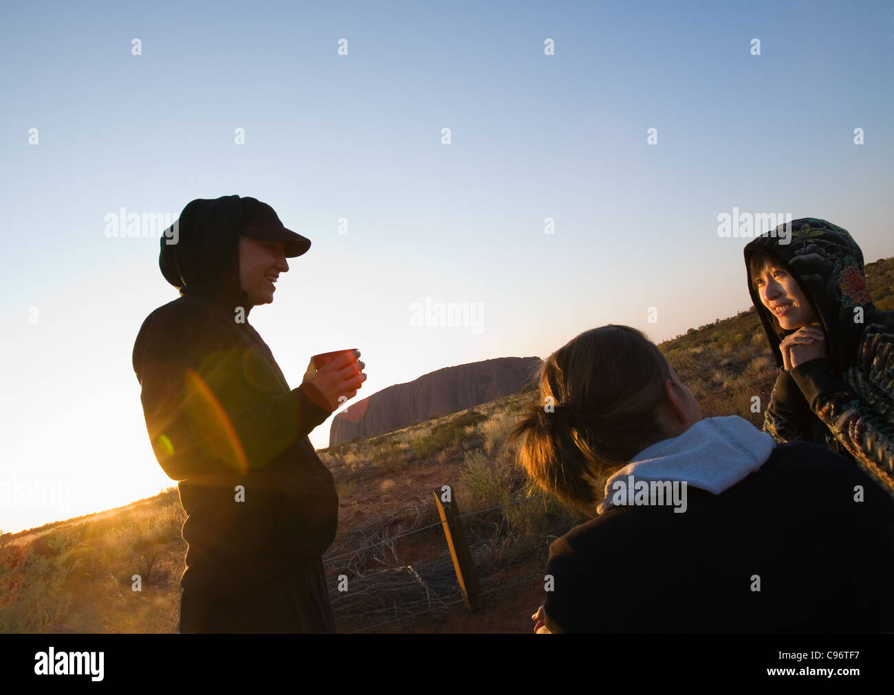Group of young tourists enjoying the sunrise at Uluru (Ayers Rocks ...