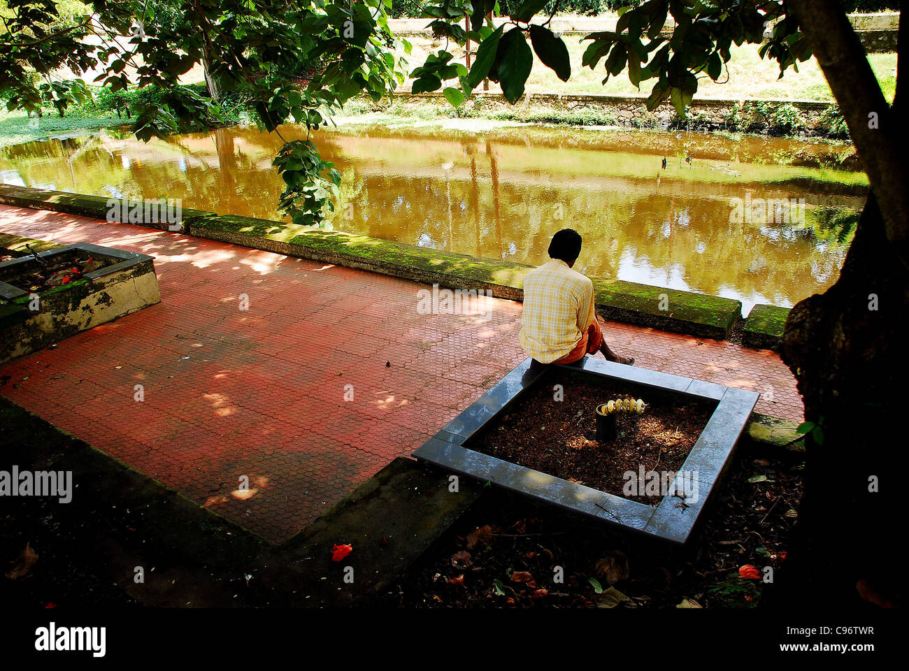 Man sitting on the walkway under a tree near Alleppey Stock Photo - Alamy