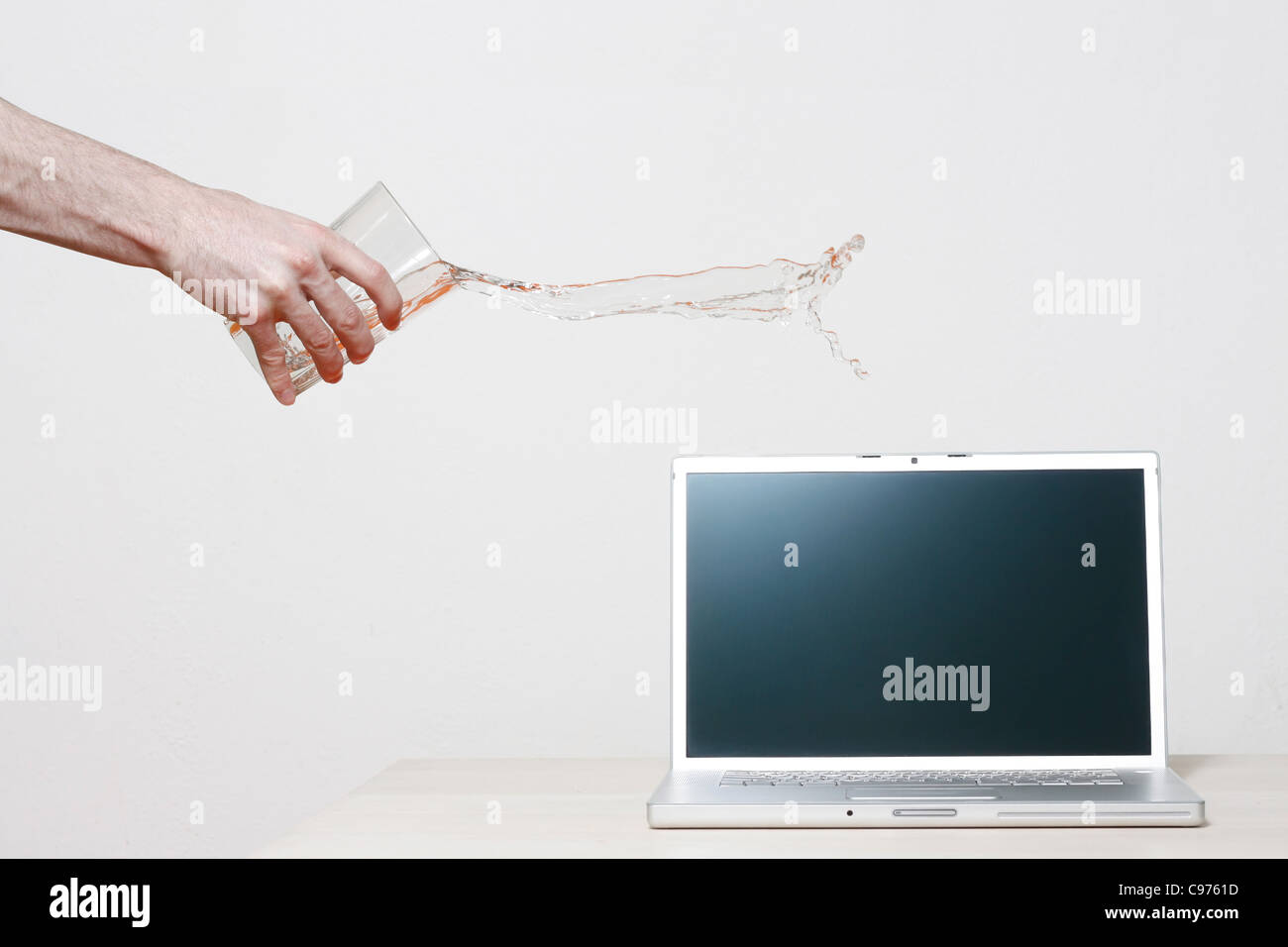 Man accidentally pouring water on laptop Stock Photo - Alamy