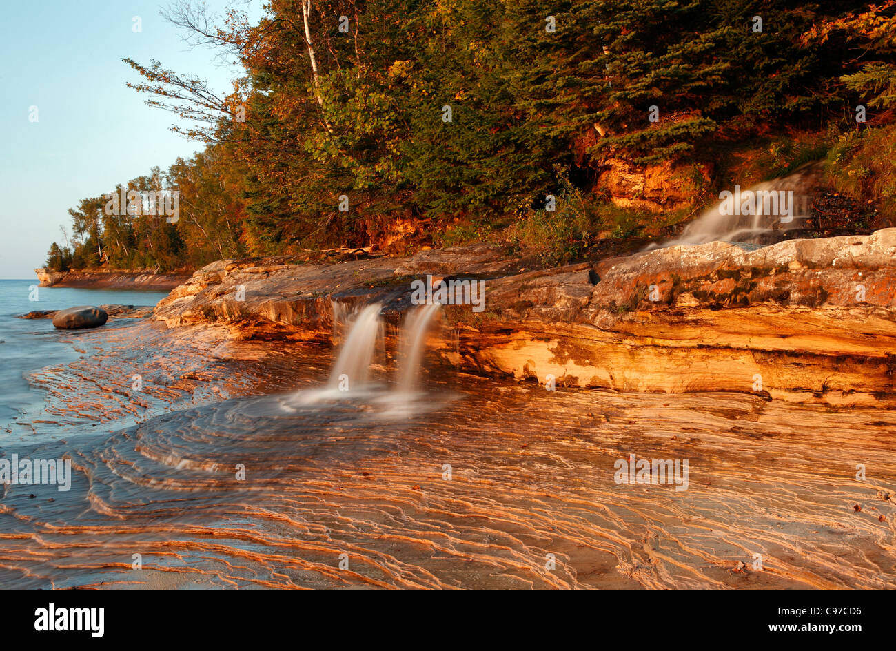 Small waterfall flows into lake Superior at Miners beach in the ...