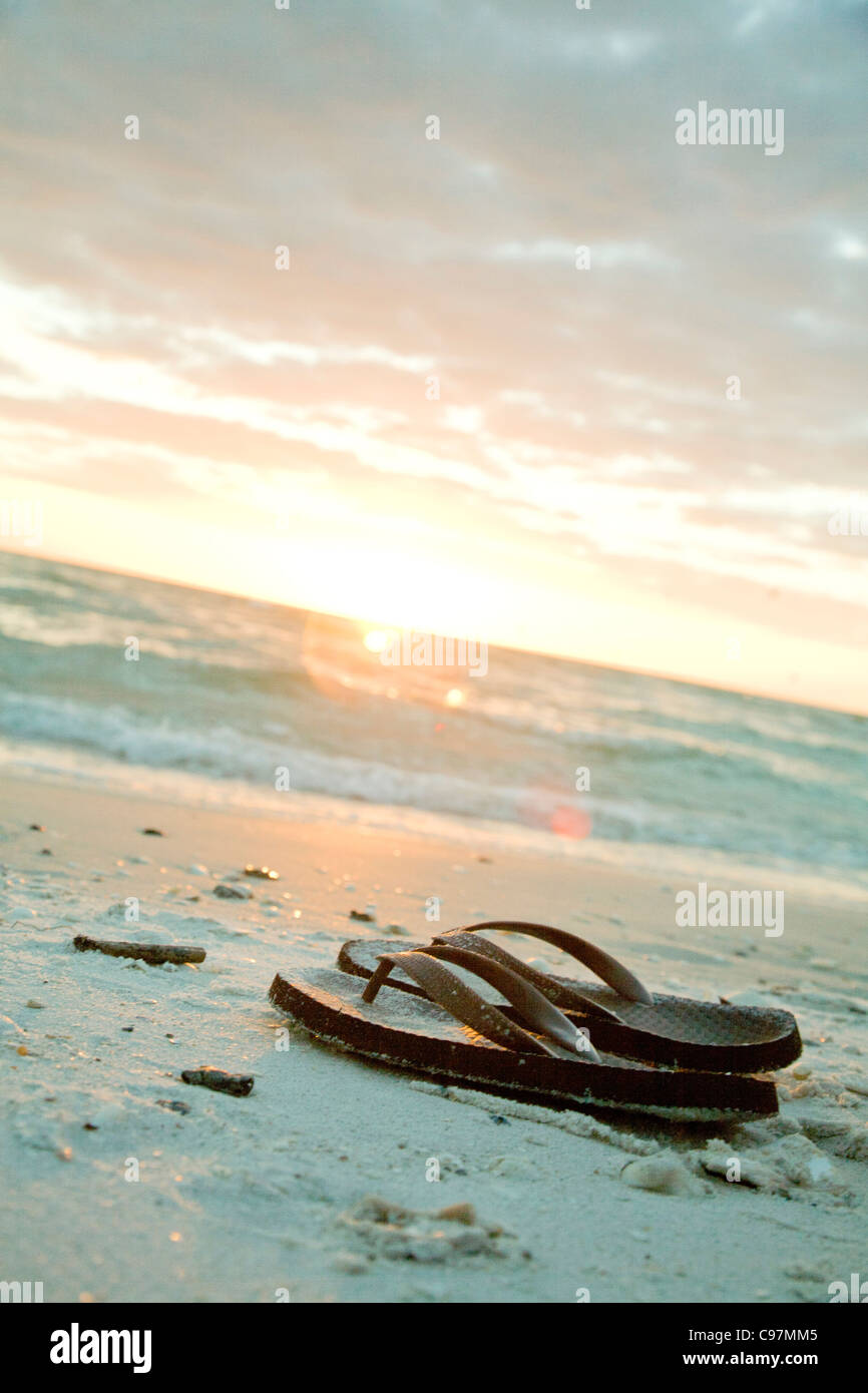brown flip flop sandals on sand in sunset Stock Photo - Alamy