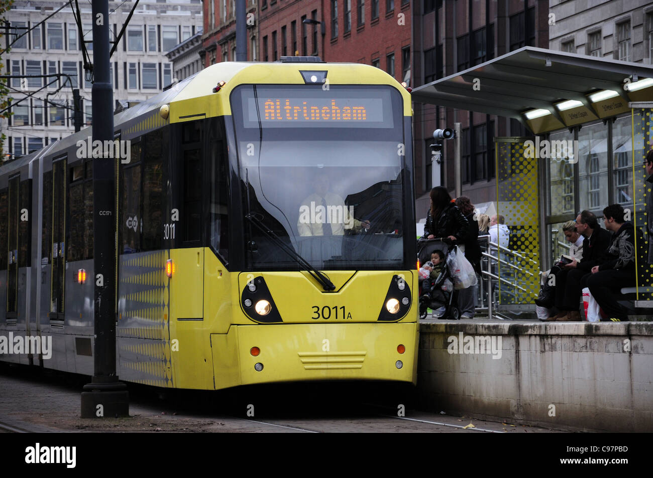 Yellow Metrolink tram at stop in central Manchester Stock Photo - Alamy