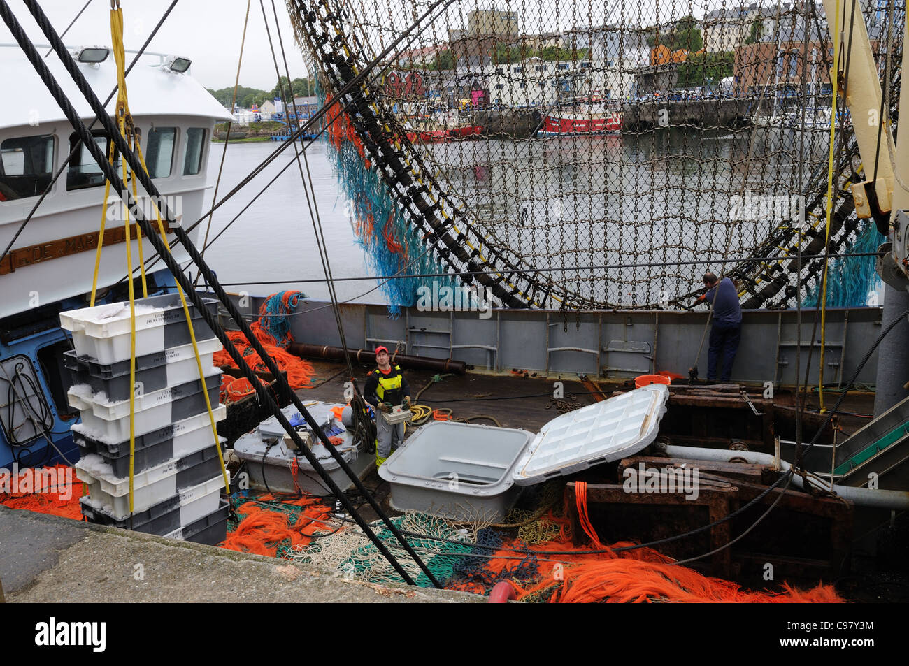 Man using machinery to lift boxes of fish prepared at sea on to a lorry ...