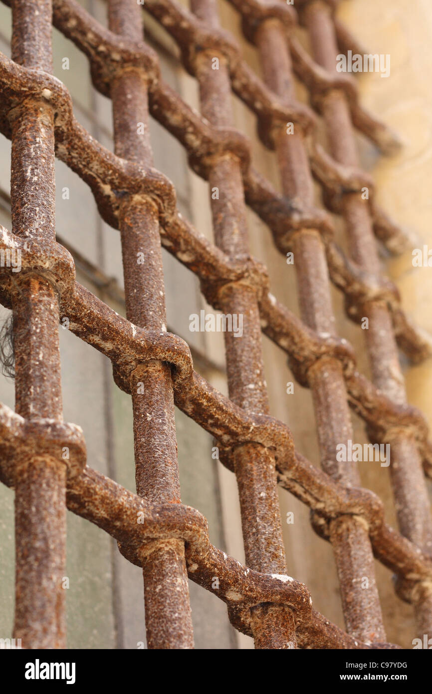 Rusty old iron grid in front of a window of an ancient building in the ...