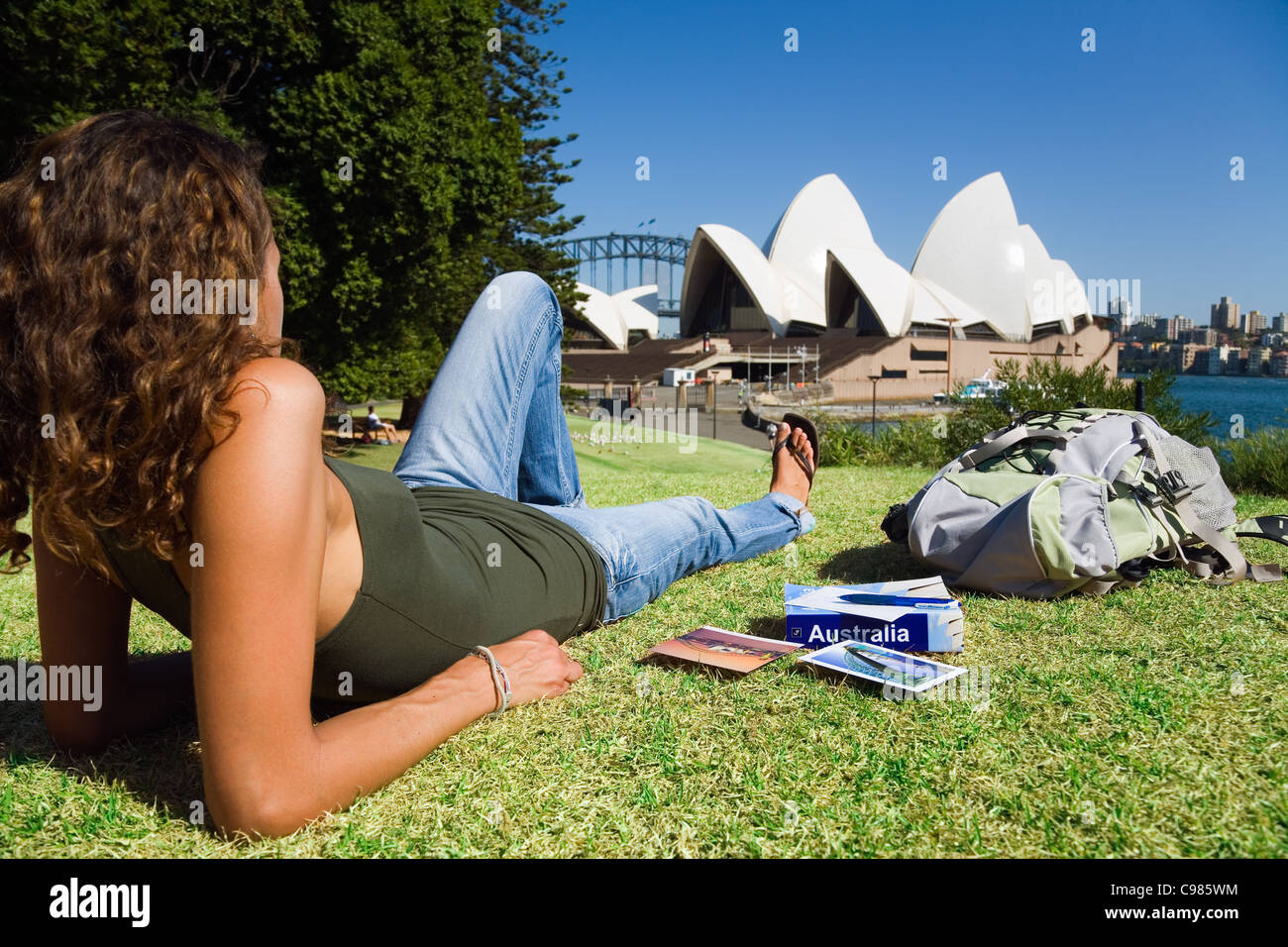A tourist relaxes in a park with Sydney Opera House in background ...