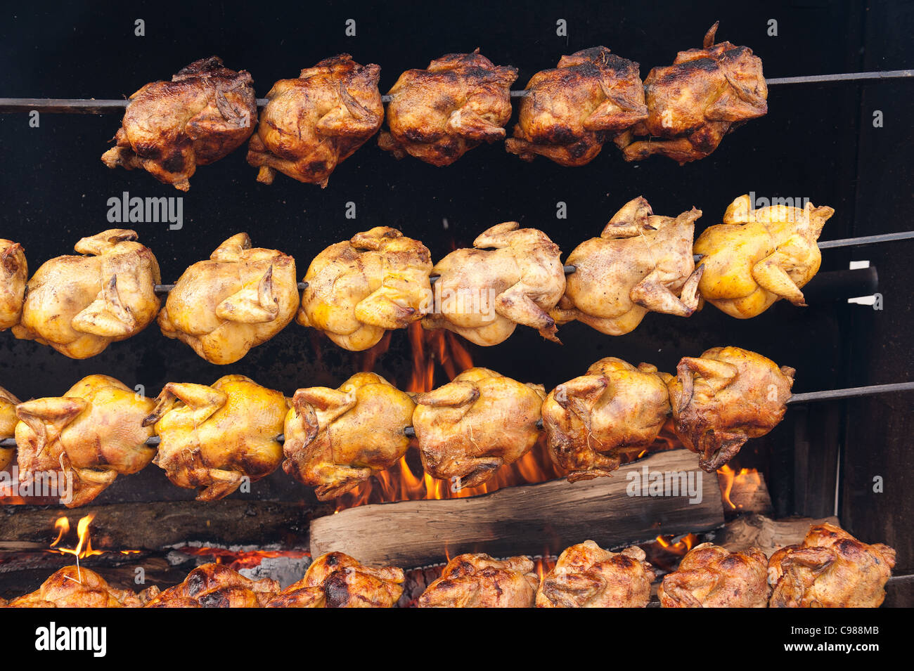 Whole grilled chicken spit roasted, cooked on outdoor fire barbecue ...
