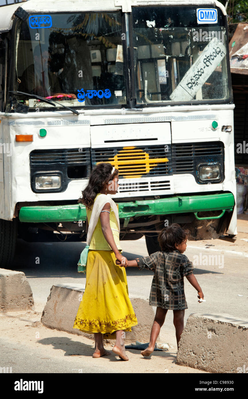 Poor indian children waiting to cross a road in front of a bus. Andhra ...