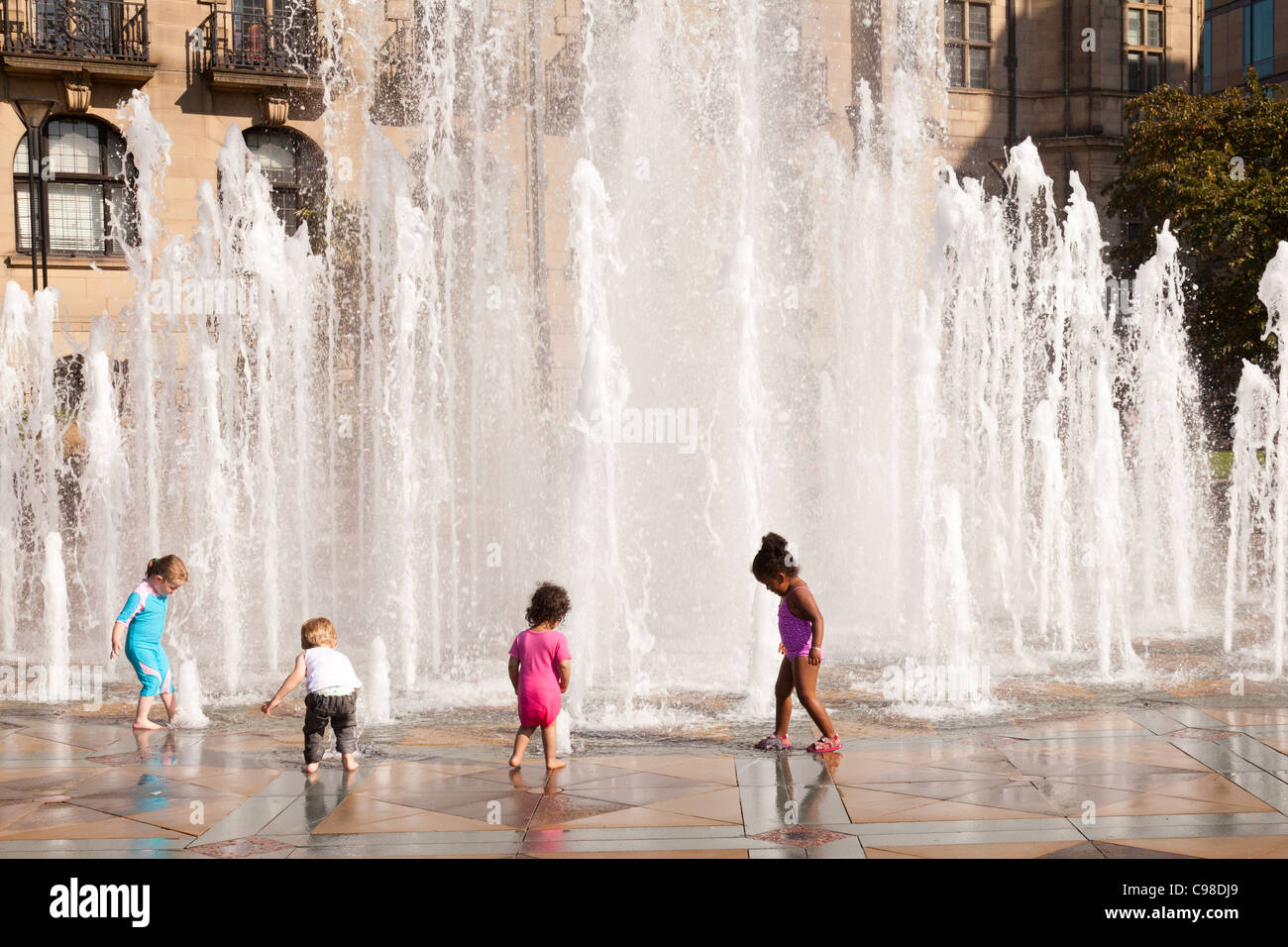 Children playing in the fountains and enjoying the sunshine in the ...