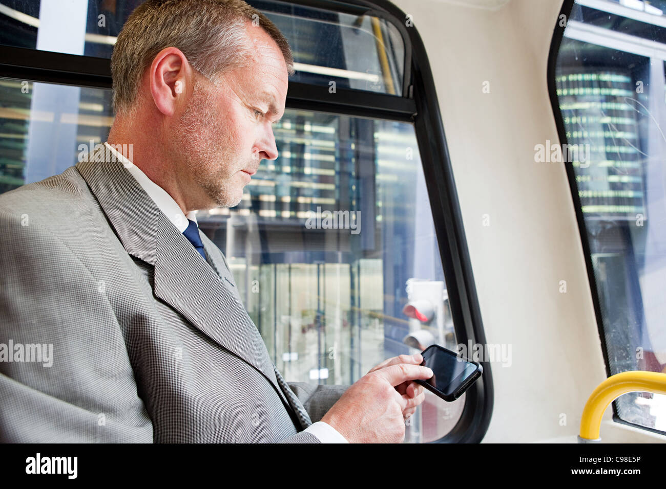 Businessman using smartphone on bus Stock Photo - Alamy