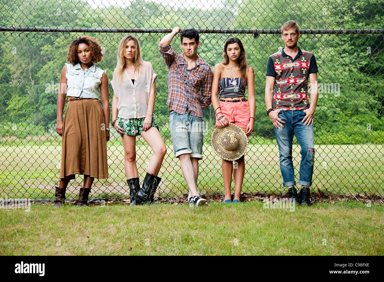 Portrait friends standing against chain link fence Stock Photo - Alamy