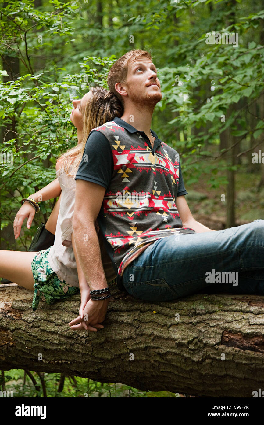 Couple leaning against each other on log forest Stock Photo - Alamy