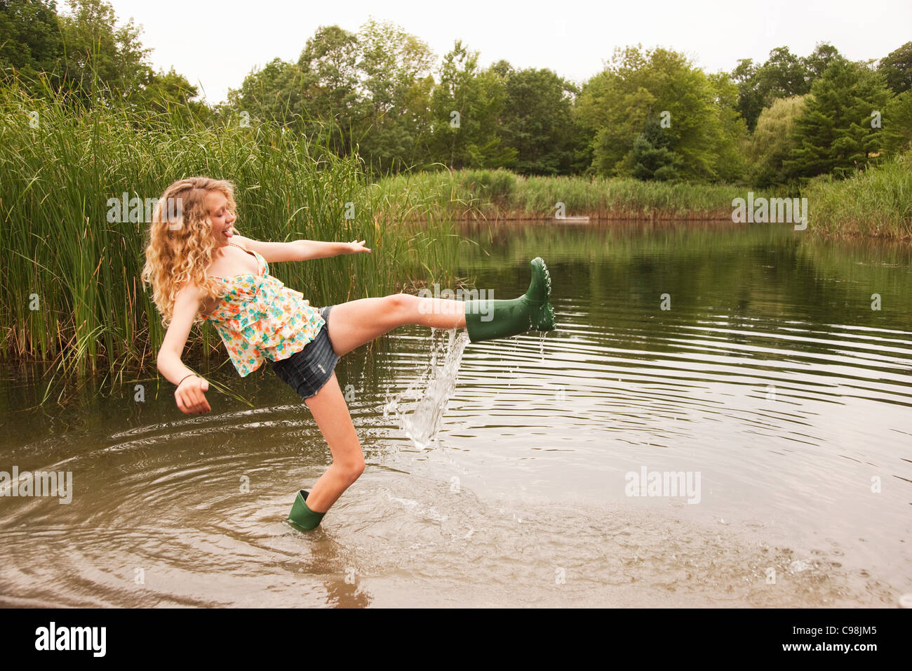 Teenage girl wading into middle lake with over-flowing wellies Stock Photo - Alamy